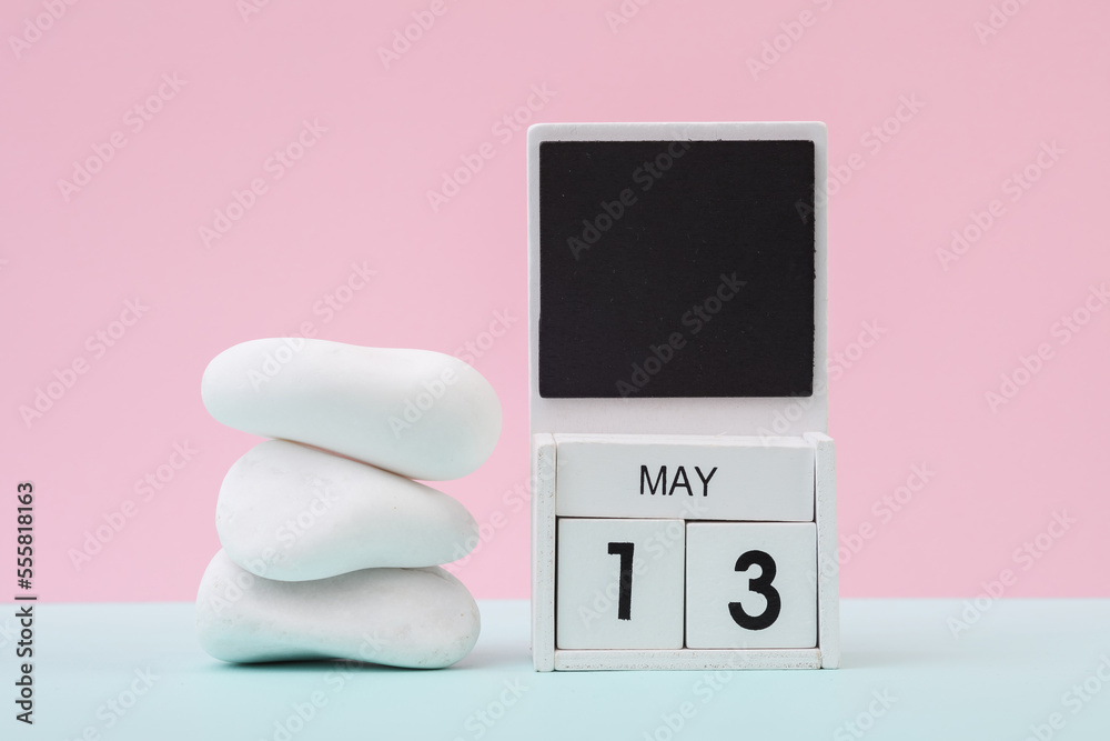 Block wooden calendar with the date may 13 and white pebbles stack on ...