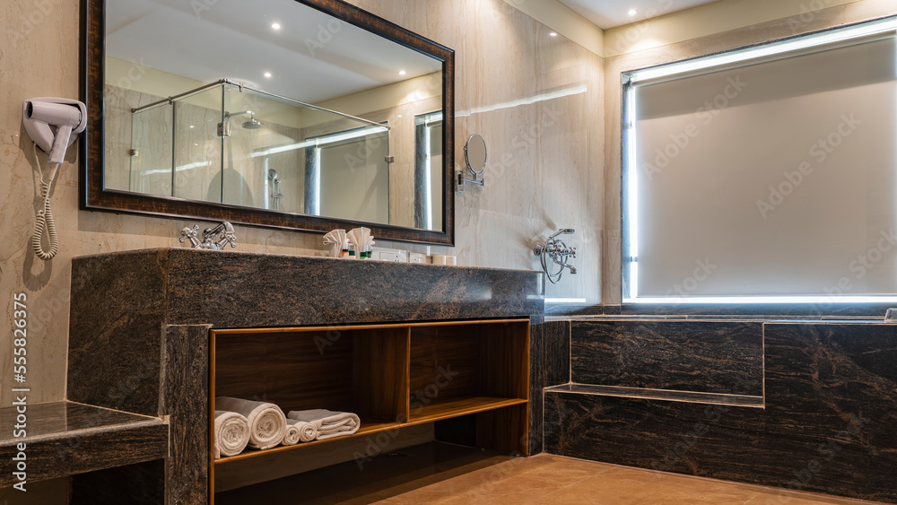 Bathroom interior. The furniture and the bathtub are lined with black marble tiles. Towels are ...