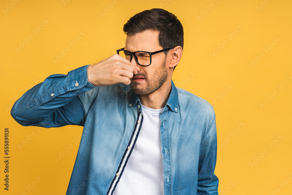 Caucasian bearded man isolated over yellow background smelling ...