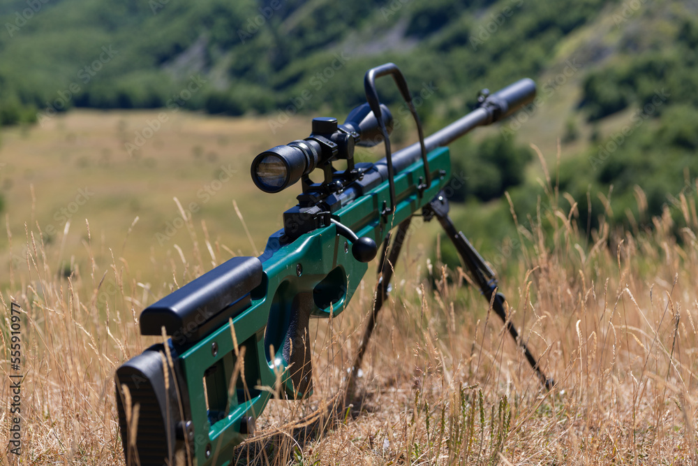 A green military sniper rifle with a scope for long distance tactical ...