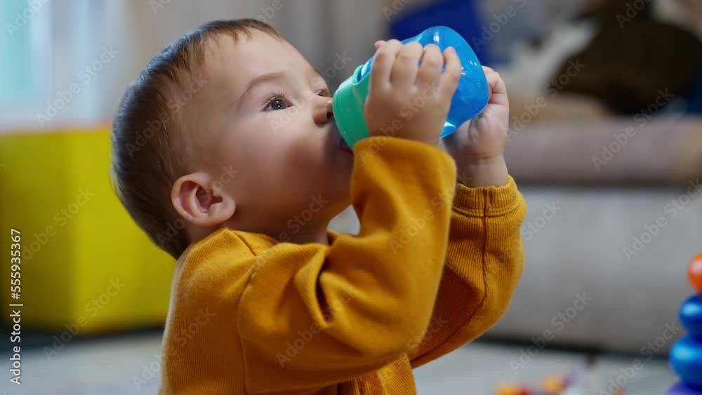 Adorable little Caucasian boy drinking water from bottle. Kid spills ...