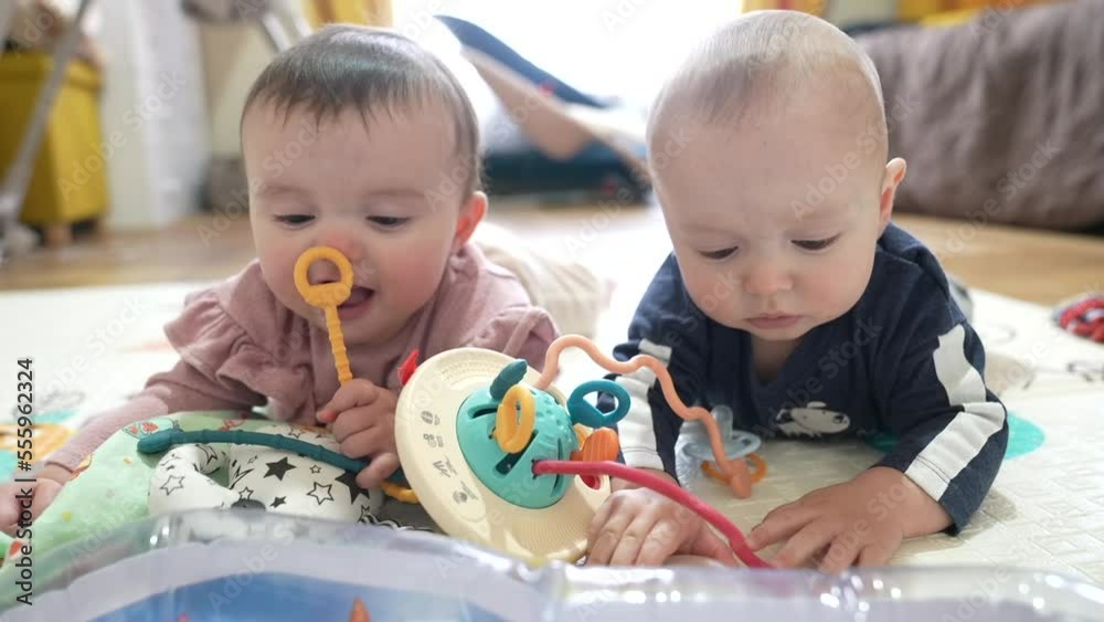 twins baby a newborns. two babies 6 months old lie on the floor playing ...
