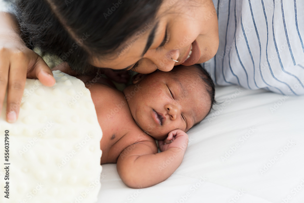 Foto de Top view mother kissing her newborn baby on bed. Young mom or nurse taking care newborn ...