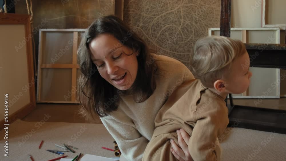 mom is playing with a baby in an art workshop. mom is fooling around ...