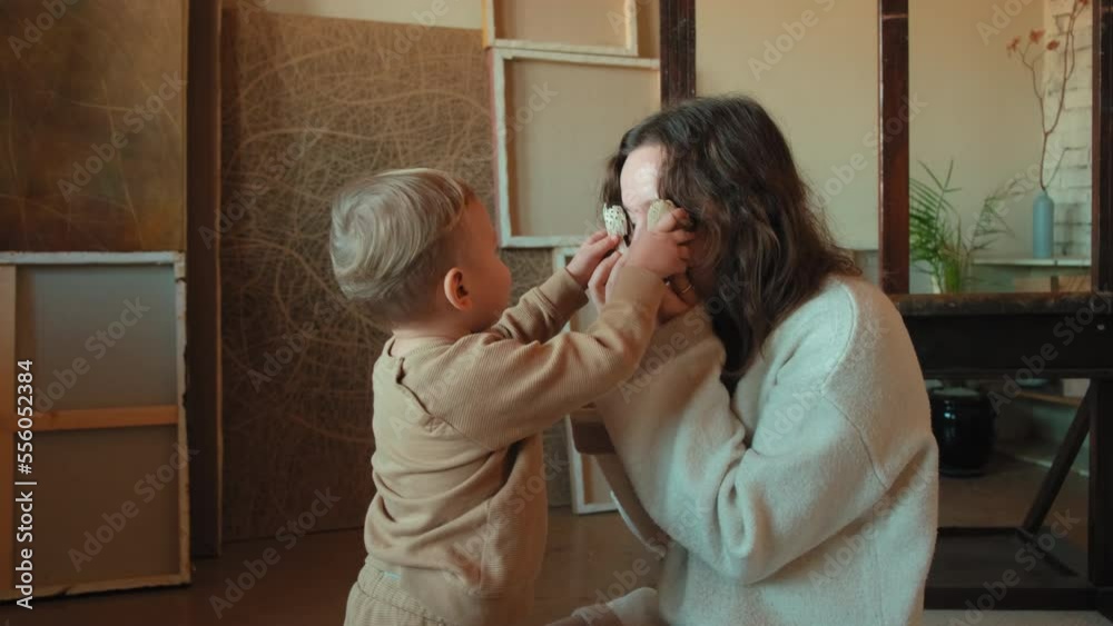 mom is playing with a baby in an art workshop. mom is fooling around ...