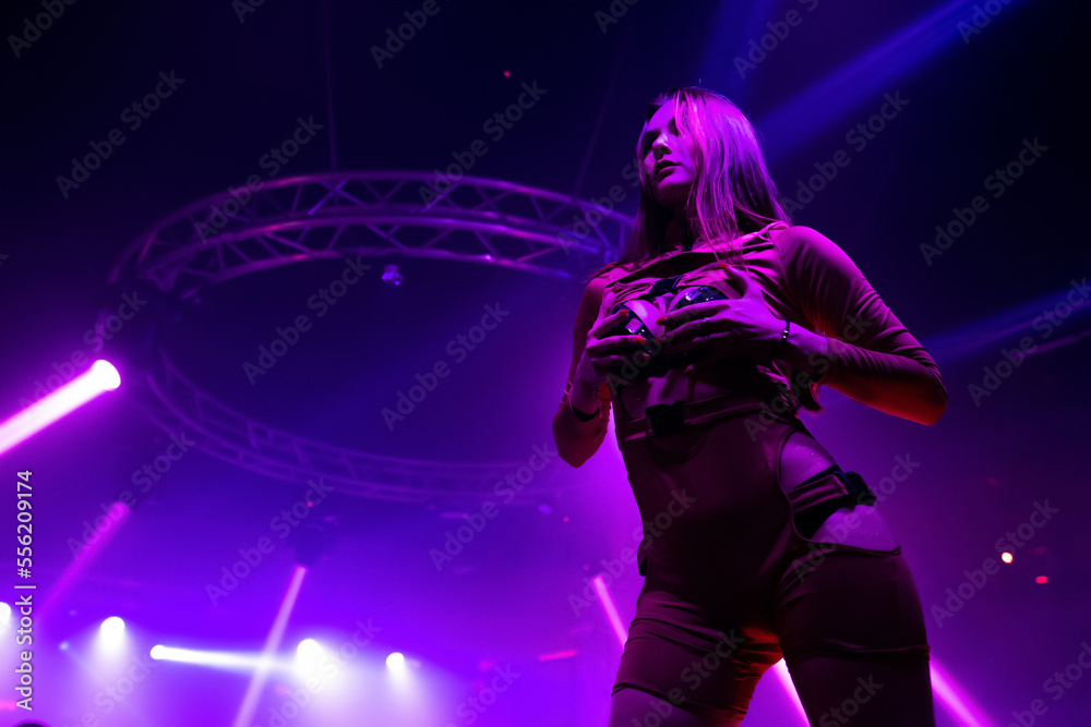 Beautiful dancer posing in a nightclub on stage. Purple lighting. Party ...
