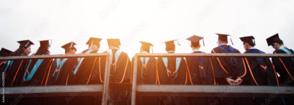 Blurred image behind the group of graduates celebrating their college ...