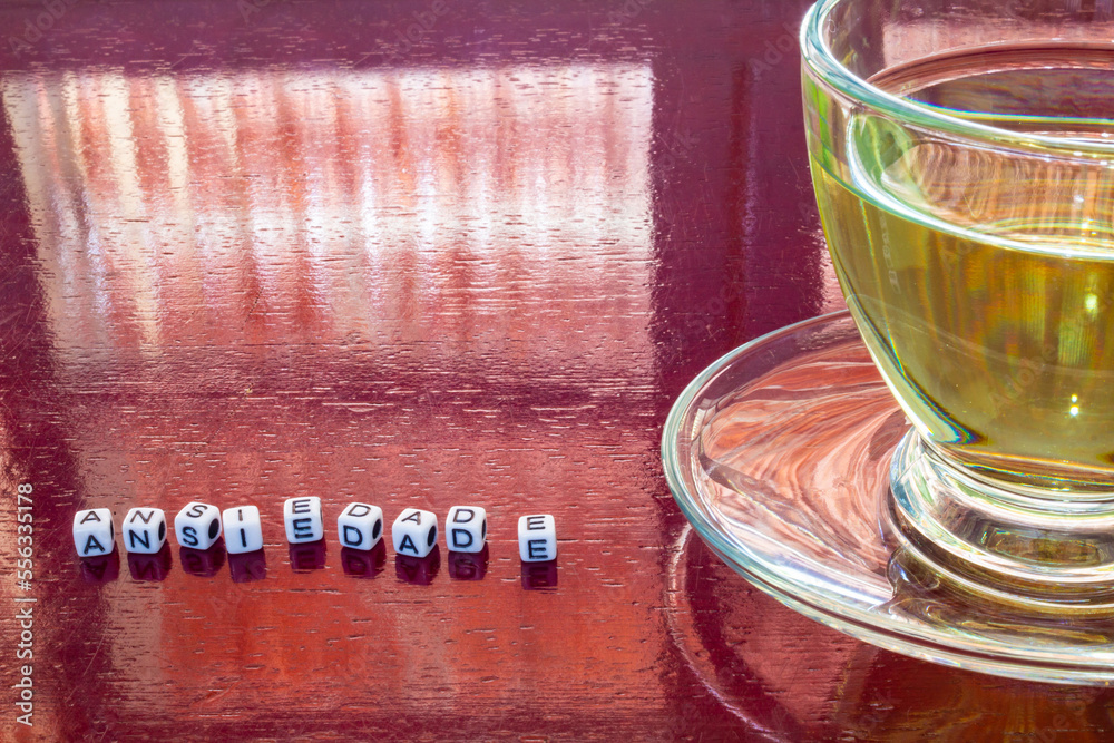 Detalhe de um copo de chá, sobre a mesa brilhante, com a palavra ...