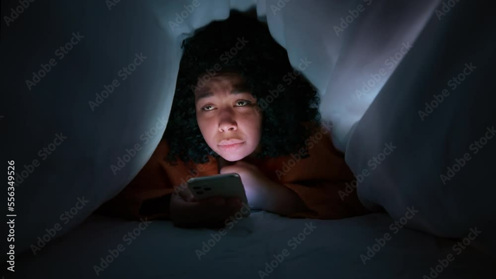African American woman hiding under blanket in bed from thunderstorm ...
