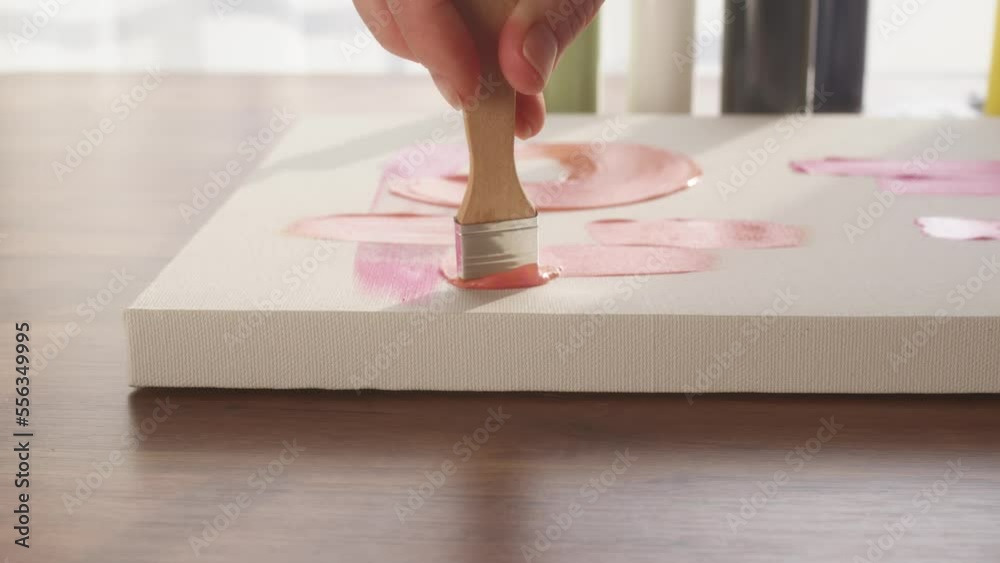 Top down young woman hand paints pink color with wide brush on small ...