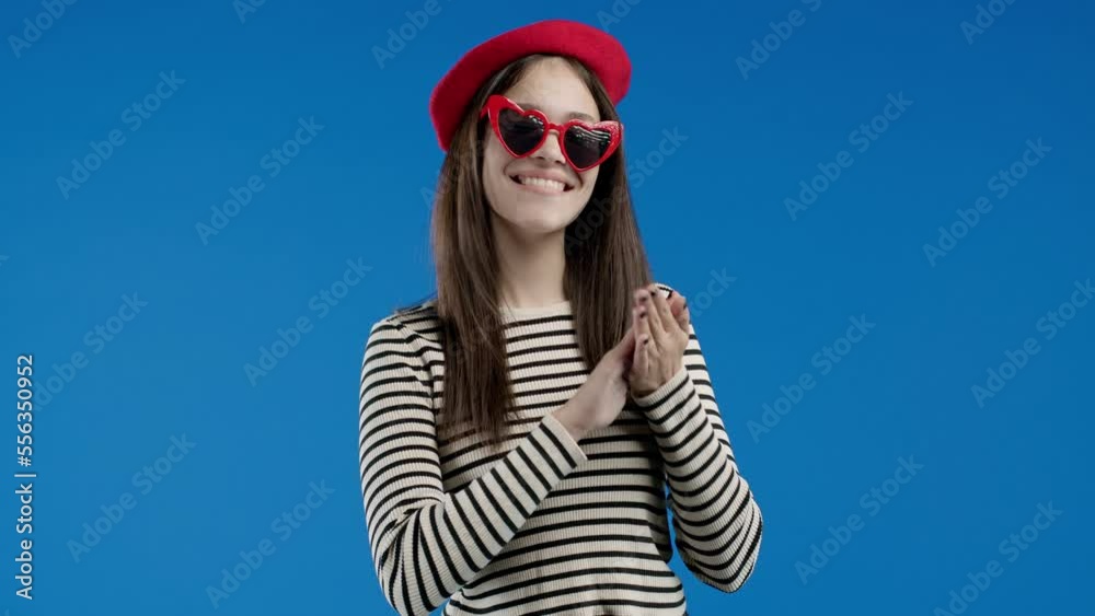 Stylish woman applauding on blue background. Smiling lady in red beret ...