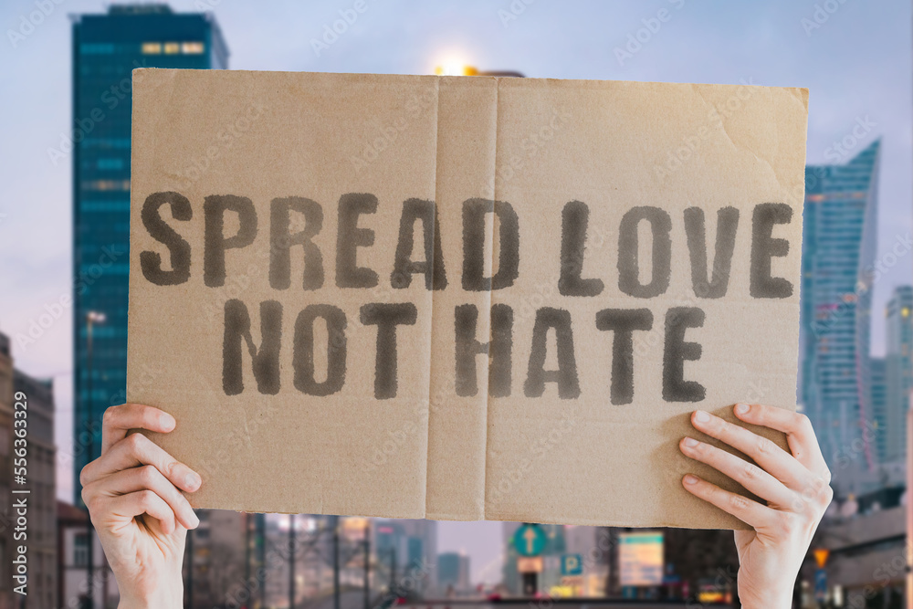 The phrase " Spread Love, Not Hate " is on a banner in men's hands with ...