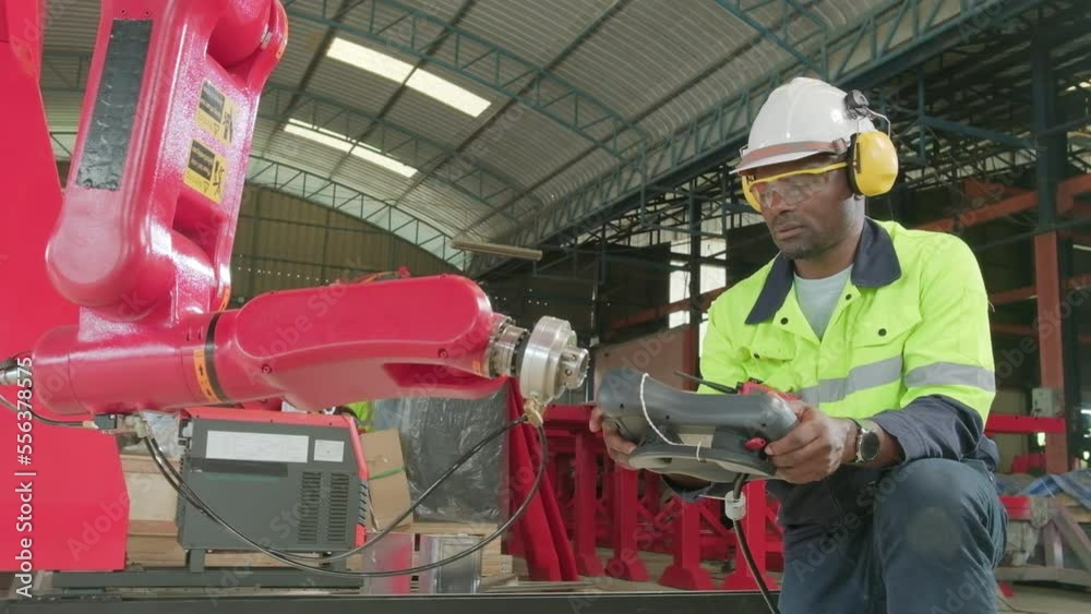 An African American production engineer test and control robotic arm in ...