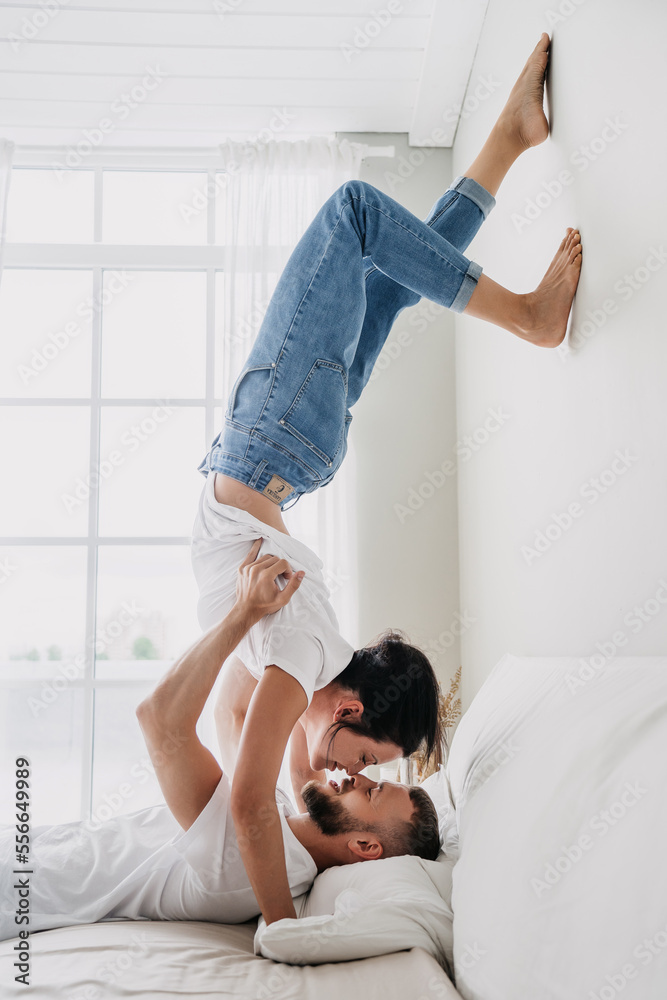 Fit Spanish young beautiful woman in casual doing handstand on bed ...