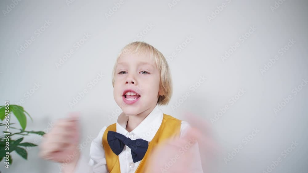 Artistic caucasian boy talks to someone behind the camera, saying HI ...
