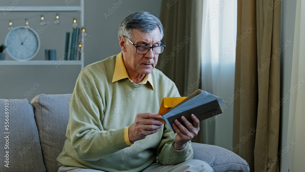 Old 60s elderly Caucasian man checking sorting letters in living room ...