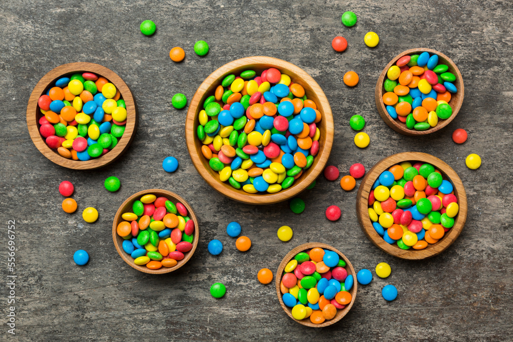different colored round candy in bowl and jars. Top view of large ...