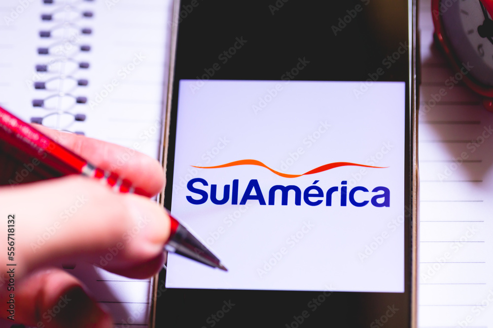 Logo da SulAmérica na tela de um celular e um homem segurando uma ...