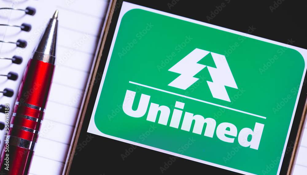 Logo da Unimed em uma tela de celular com caneta e caderno na ...
