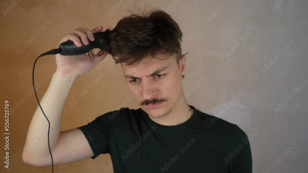 A man in the process of cutting his own hair. Cuts hair very short ...