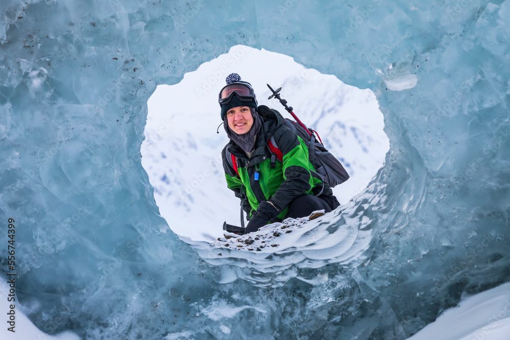 A hiker looks through a hole in an iceberg frozen in place in the ...