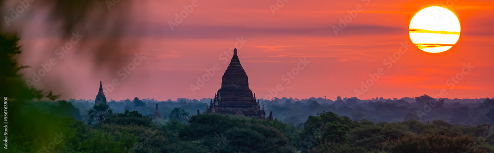 Silhouettes of pagodas with the sun rising above the Plain of Bagan at ...