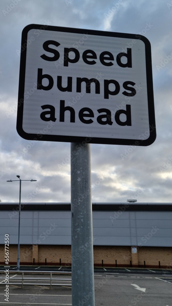 Square traffic sign on a grey pole in an empty carpark with a white ...