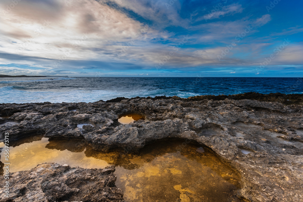 Rock formations and sunlit tidal pools along the coastal shore at ... Rock formations and sunlit tidal pools along the coastal shore at ...
