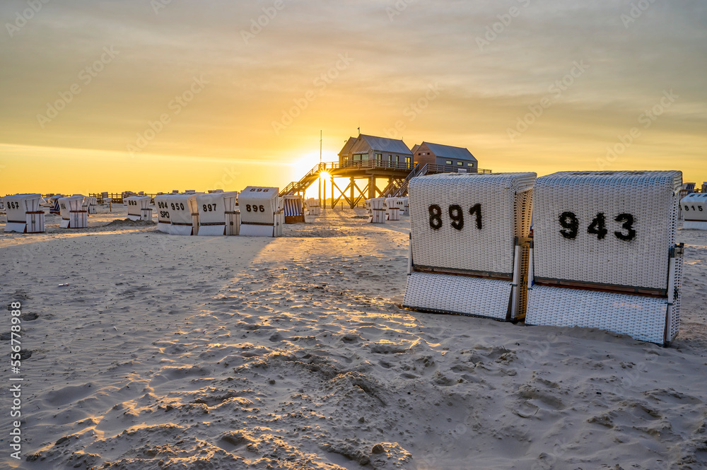 Sandy beach with Strandkorb beach chairs and resort facility buildings ...