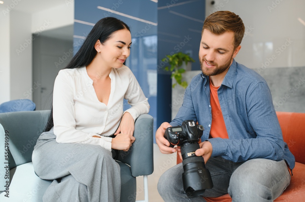 Photographer in office shows photo model in camera. Consultant adjusts ...