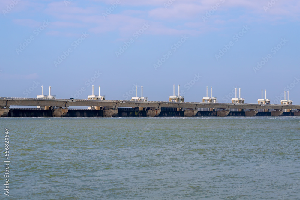 Cement concrete dam and white wind turbine, The Delta Works is a ...