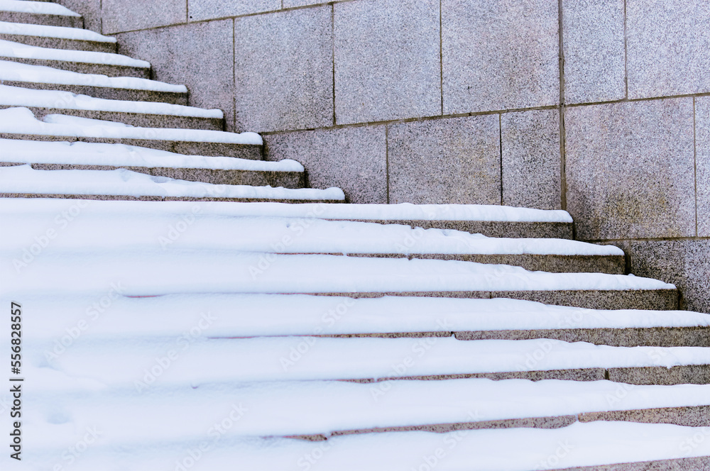 The steps of the granite stairs are covered with snow during a snowfall ...