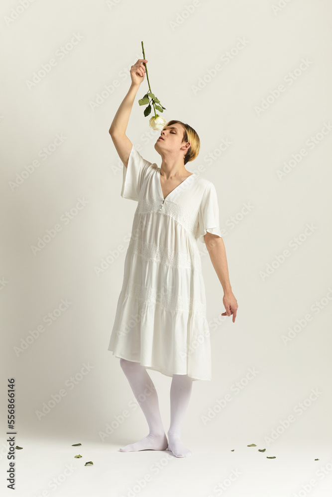 Handsome male model wearing white romantic outfit smelling white rose ...