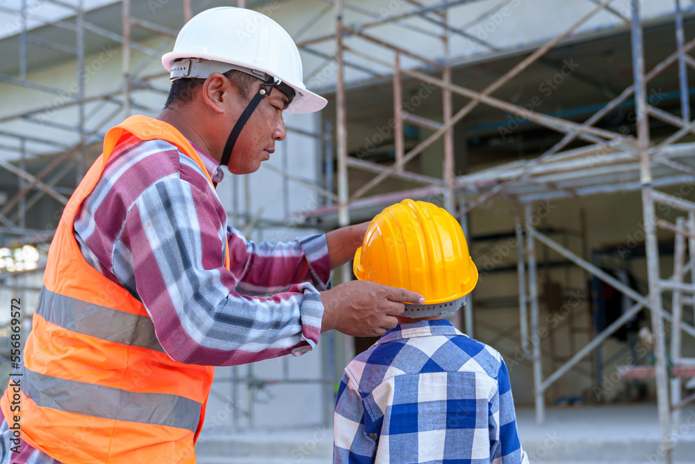 Male contractor holding boy's hand standing looking at building under ...