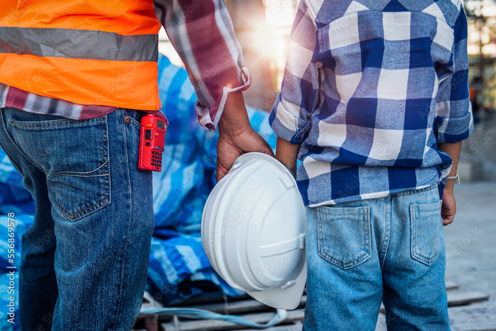 Male contractor holding boy's hand standing looking at building under ...