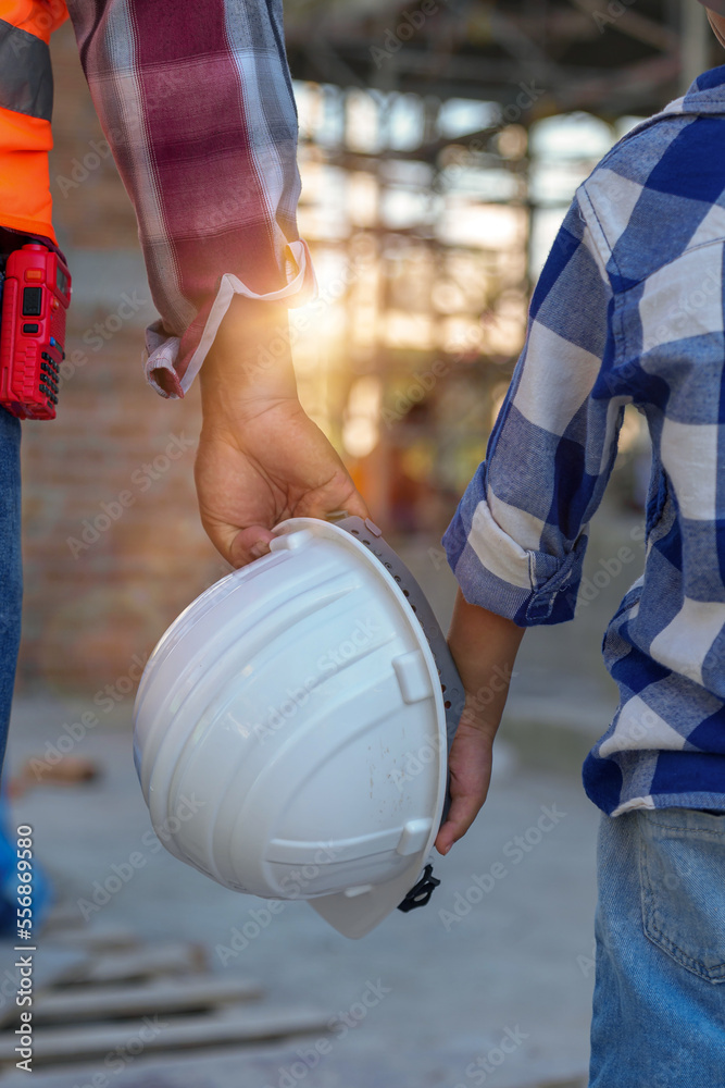 Male contractor holding boy's hand standing looking at building under ...