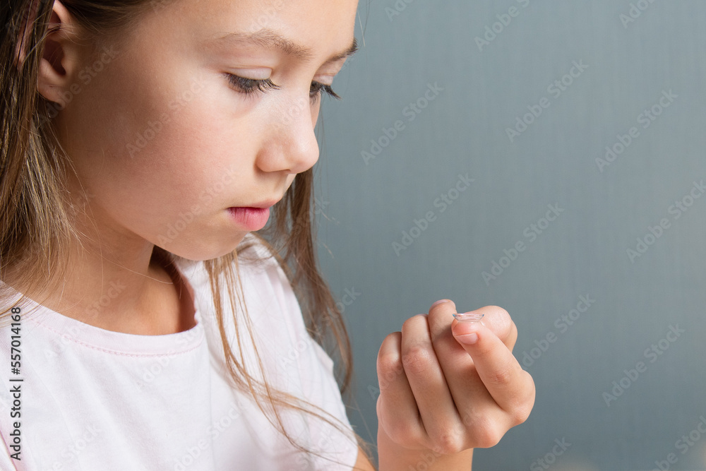 Contact lens for kids, safe to wear. Cute little girl putting silicone ...