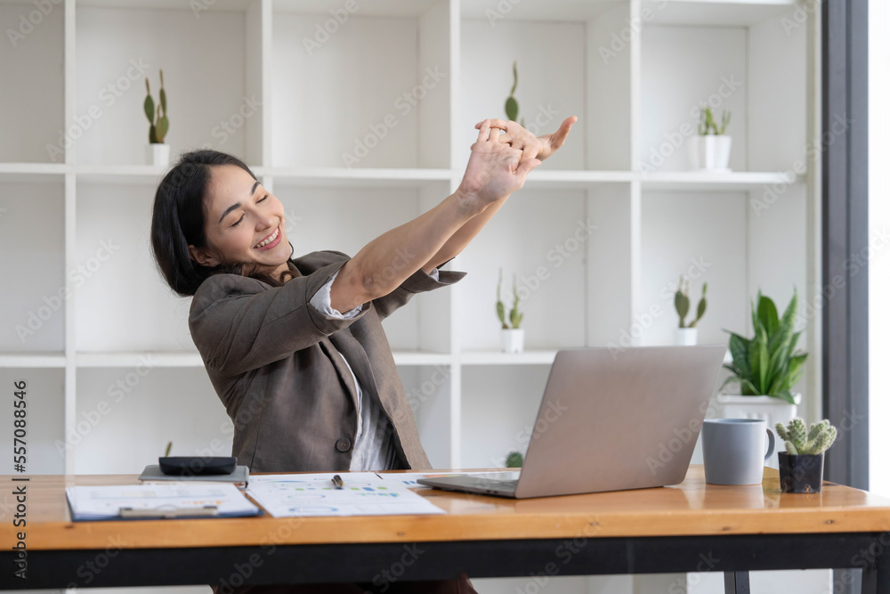 Asian businesswoman stretches her arms to relax her tired muscles from ...