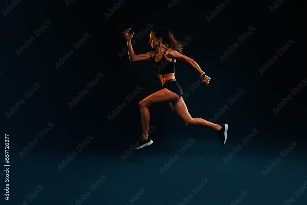 Sprinter against a black background. Muscular female running and ...
