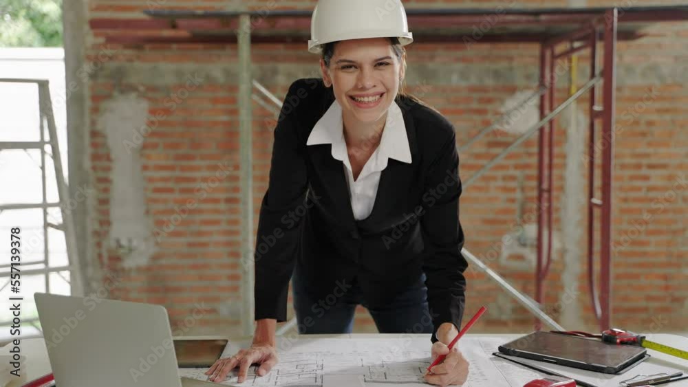 Young female architect checking blueprints inside a building at a ...