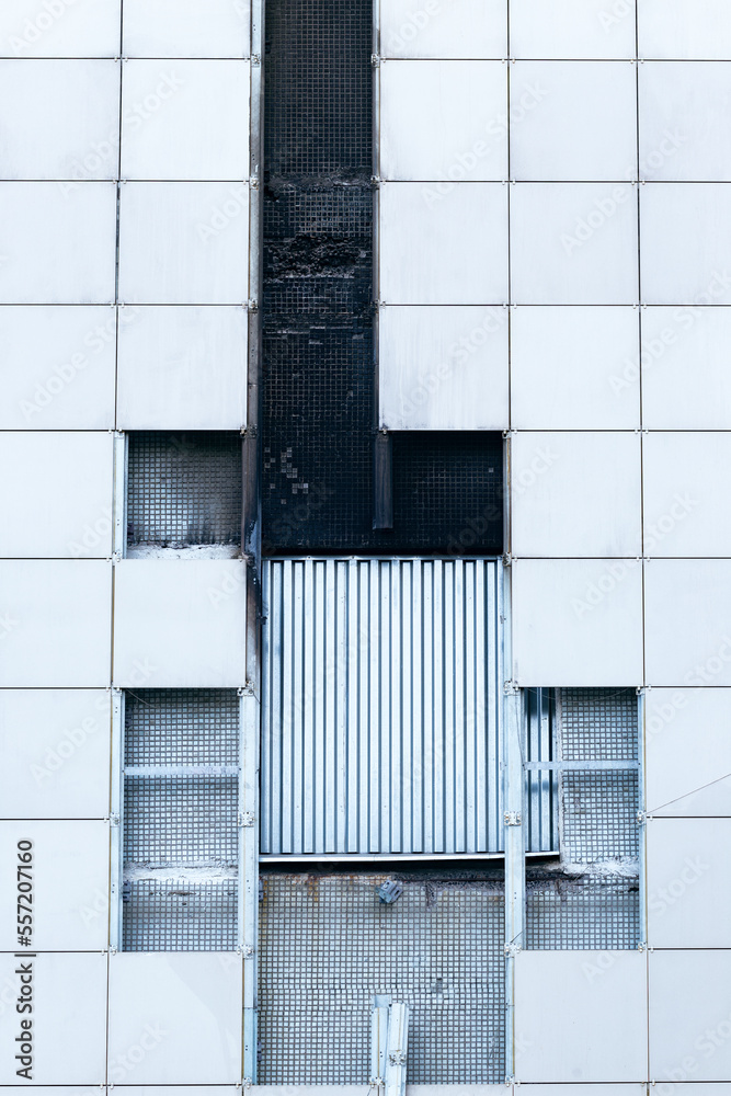 Broken, badly fixed wall of an industrial building. Fallen off cladding ...