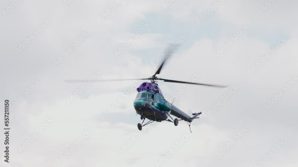 Violet soviet military helicopter Hoplite Mi-2 flying against blue sky ...