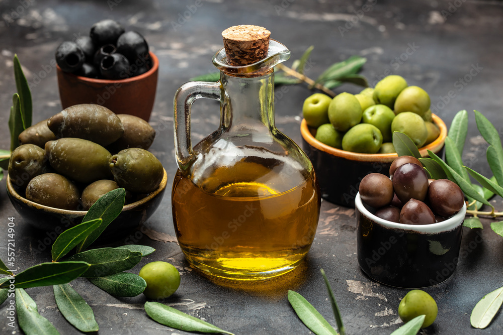 Different types of olives in olive bowls and olive oil on a dark background, Olive concept ...