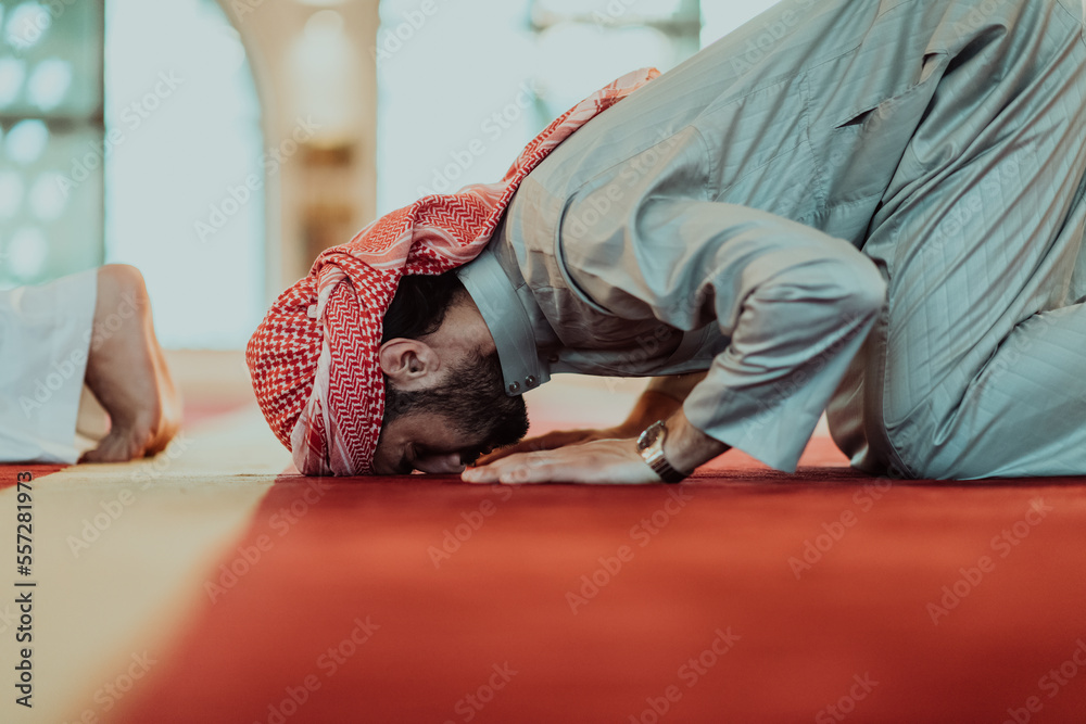 A group of Muslims in a modern mosque praying the Muslim prayer namaz ...
