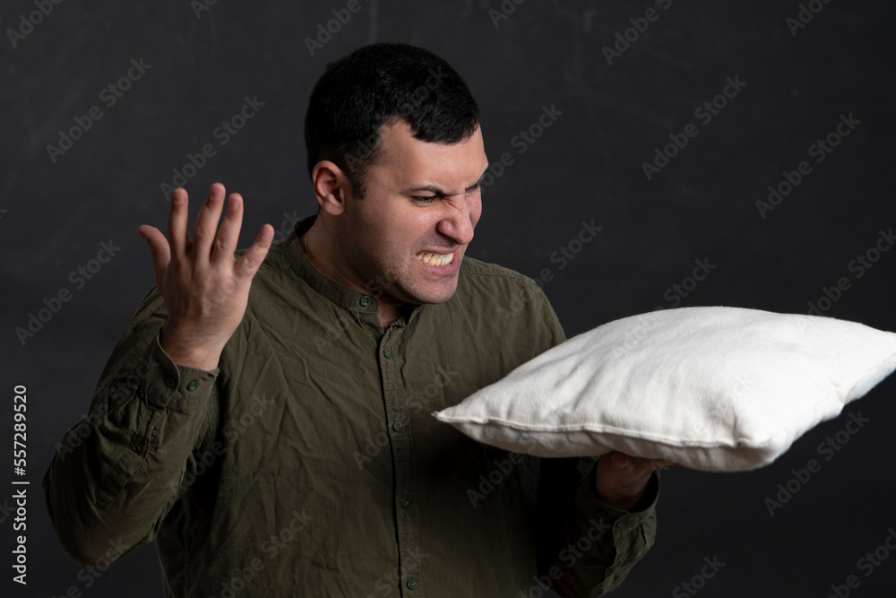 Emotional portrait of a man 30-35 years old, holding a pillow in his ...