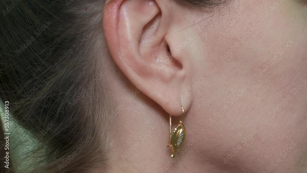 Close-up view of ear of caucasian young brunette woman listen music ...