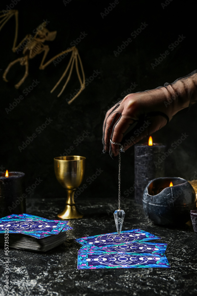Fortune teller using pendulum and tarot cards to read future on dark ...