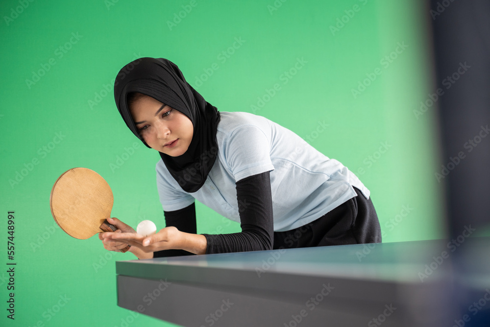 Young asian girl in hijab playing table tennis on green background ...