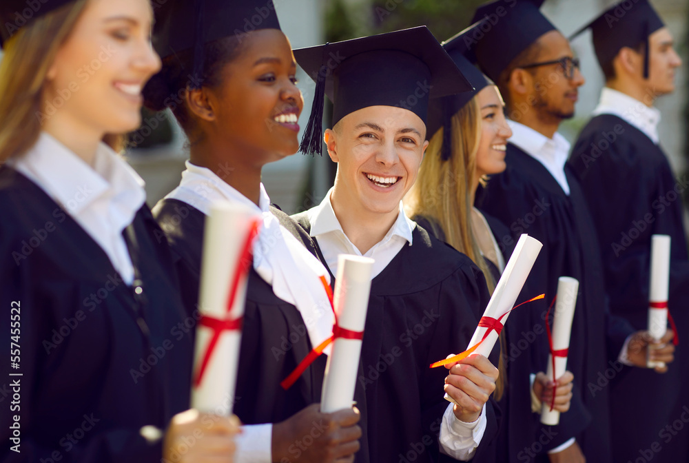 Happy graduate man in graduation gown and cap with diploma posing for ...