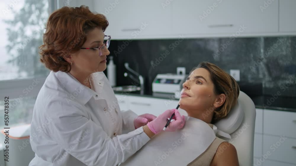 Beautician drawing correction lines on woman face before lifting ...